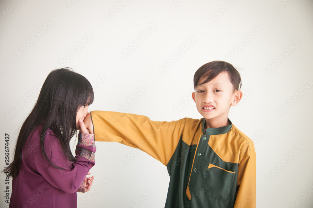 Two young Malay muslim siblings in traditional outfit showing forgiving ...