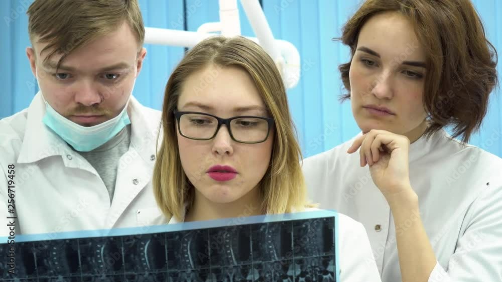 Three young doctors looking at full body x-ray radiographic image, ct ...