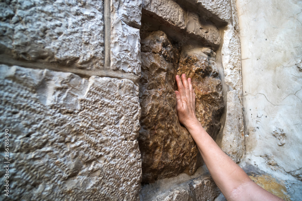 Close up of young man's hand touching an old square stone with a cavity ...