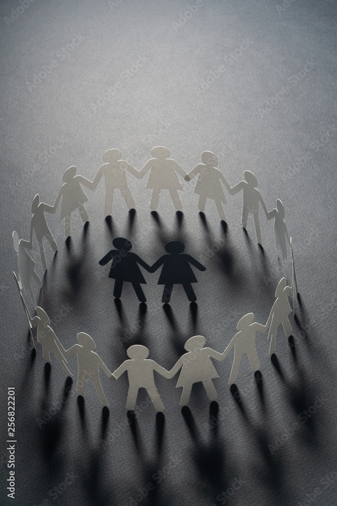 Paper figure of female couple surrounded by circle of paper people ...