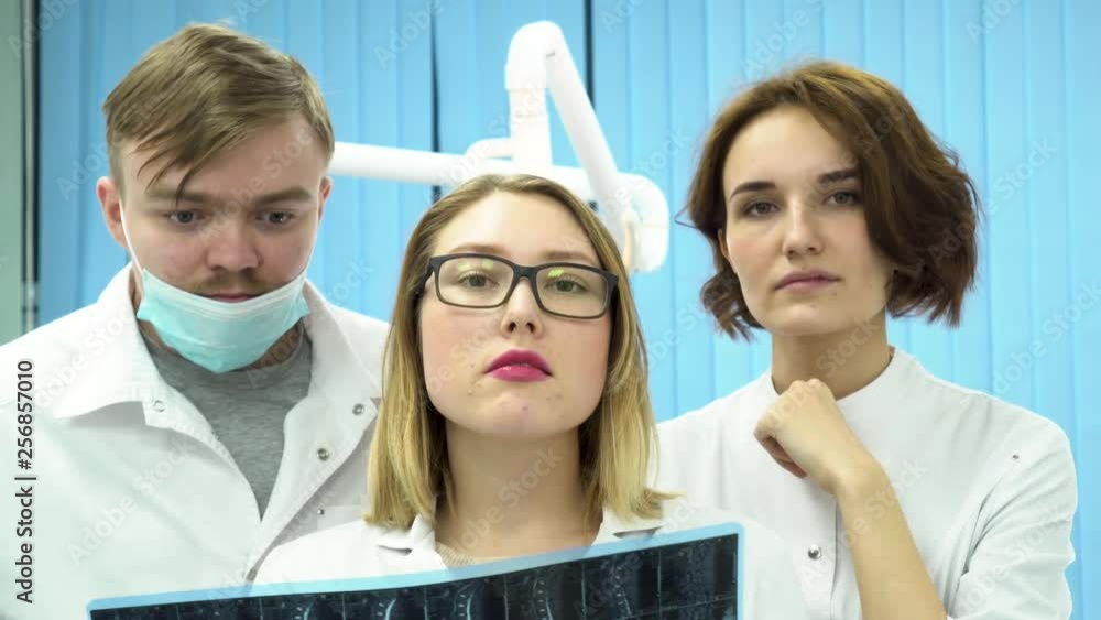 Three young doctors looking at full body x-ray radiographic image, ct ...