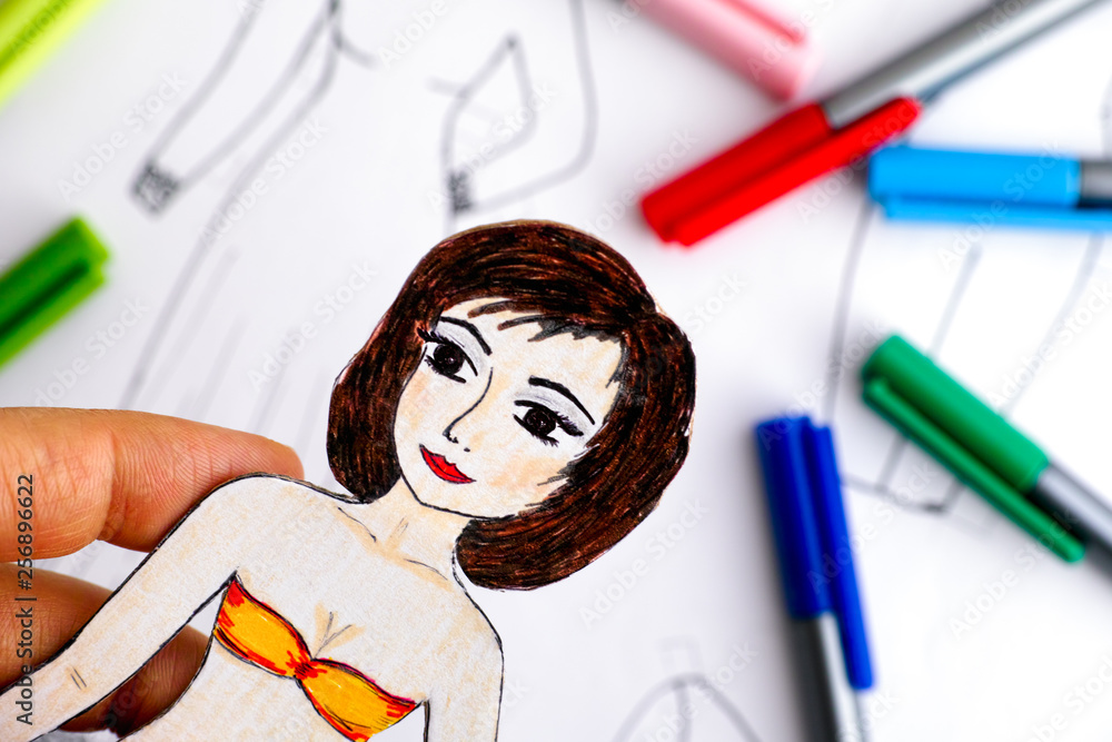 Paper doll in person hand against paper with drawing clothes and ...