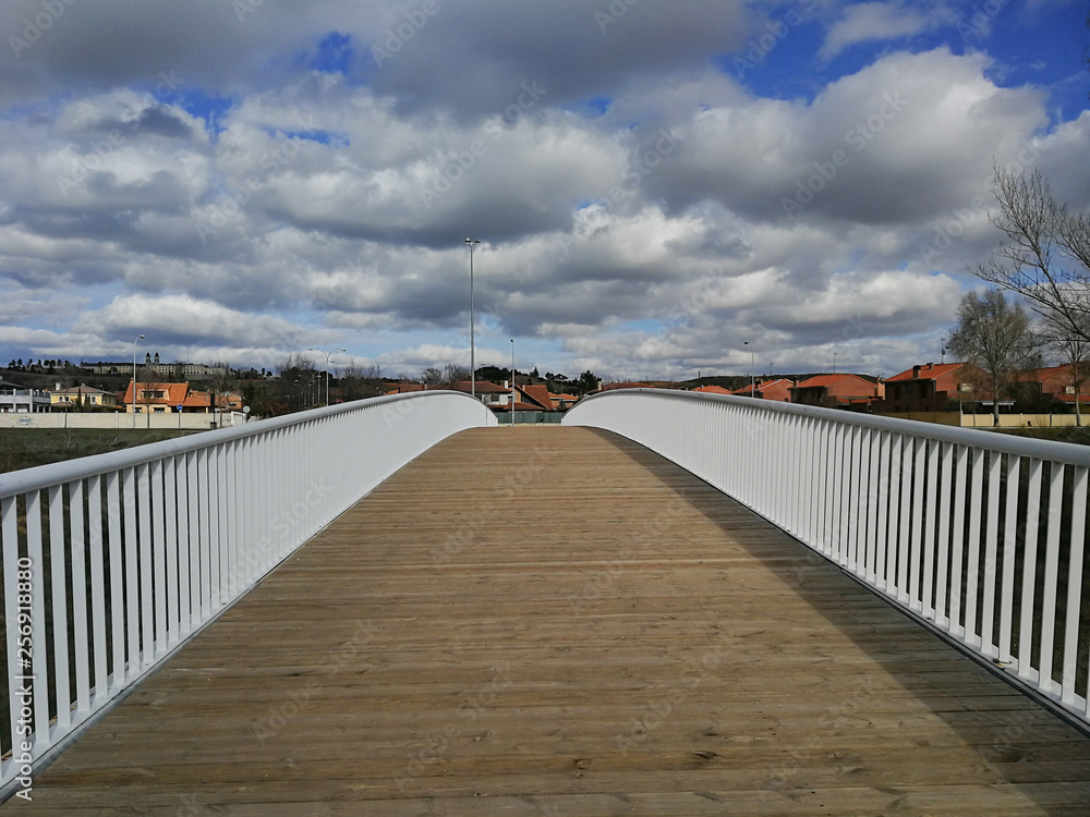 Pasarela peatonal sobre río con el suelo de tablas de madera ...