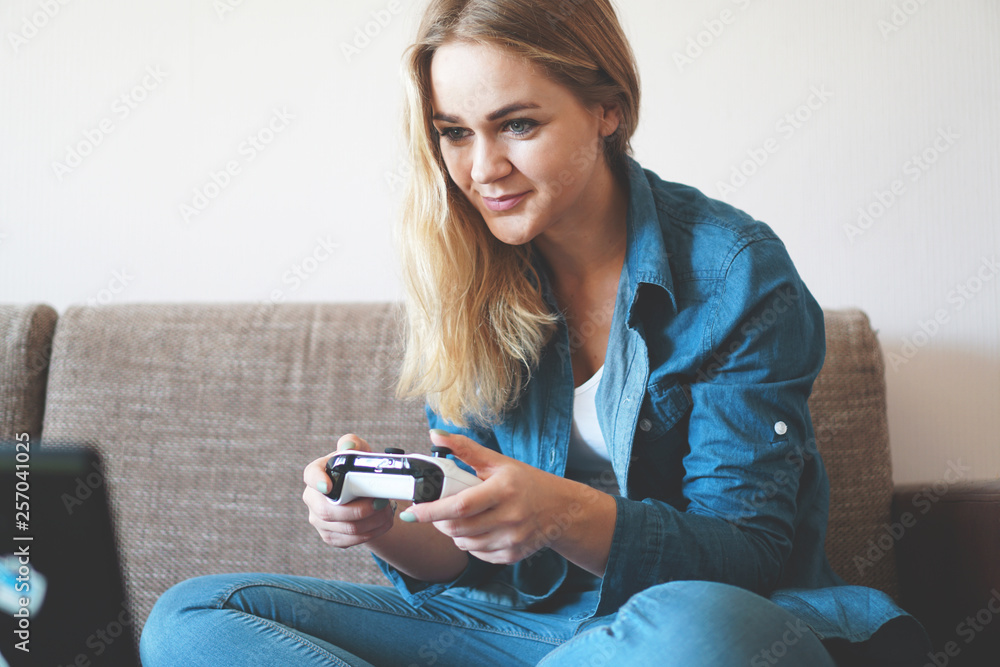 Girl gamer plays with a wireless gamepad while looking at the screen in ...