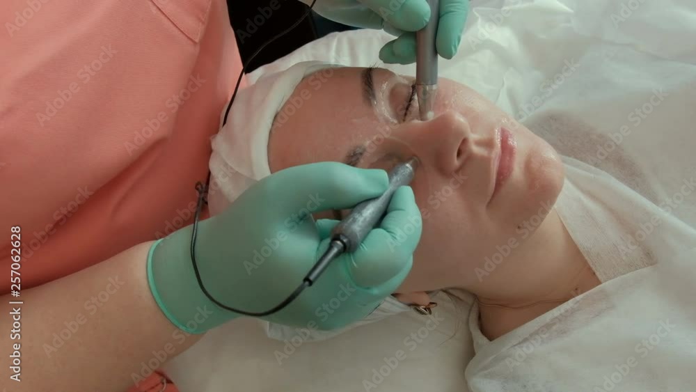 The hands of the beautician conduct electrodes microcurrent massage ...