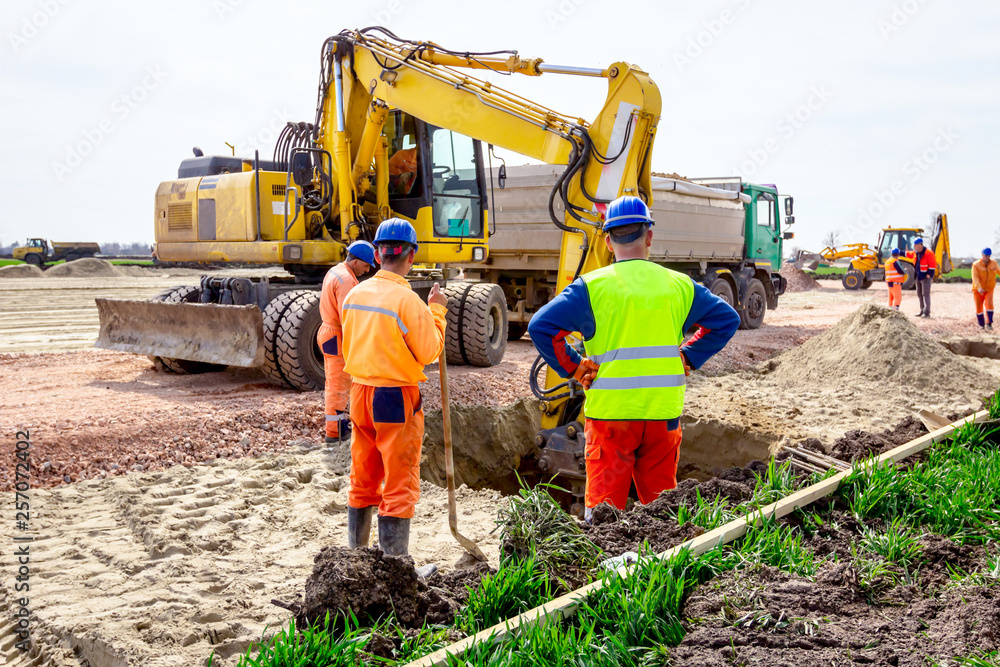 Group of workers with safety vests and helmets at construction site ...