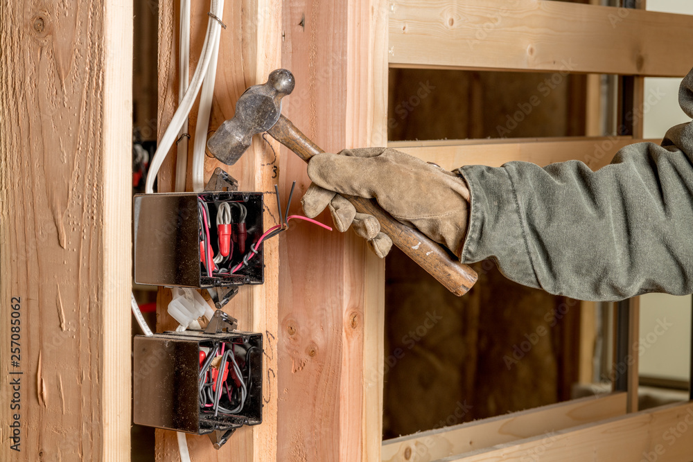 Handy man uses a hammer to install electrical boxes in a new home Stock ...