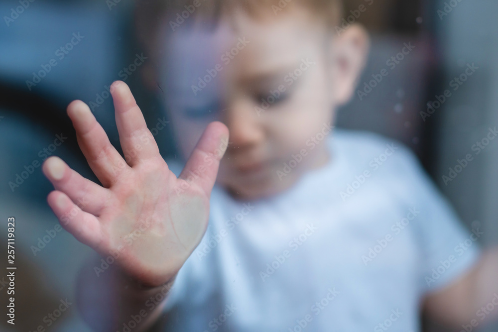 Child's small hand is pressed against the window glass with reflection ...