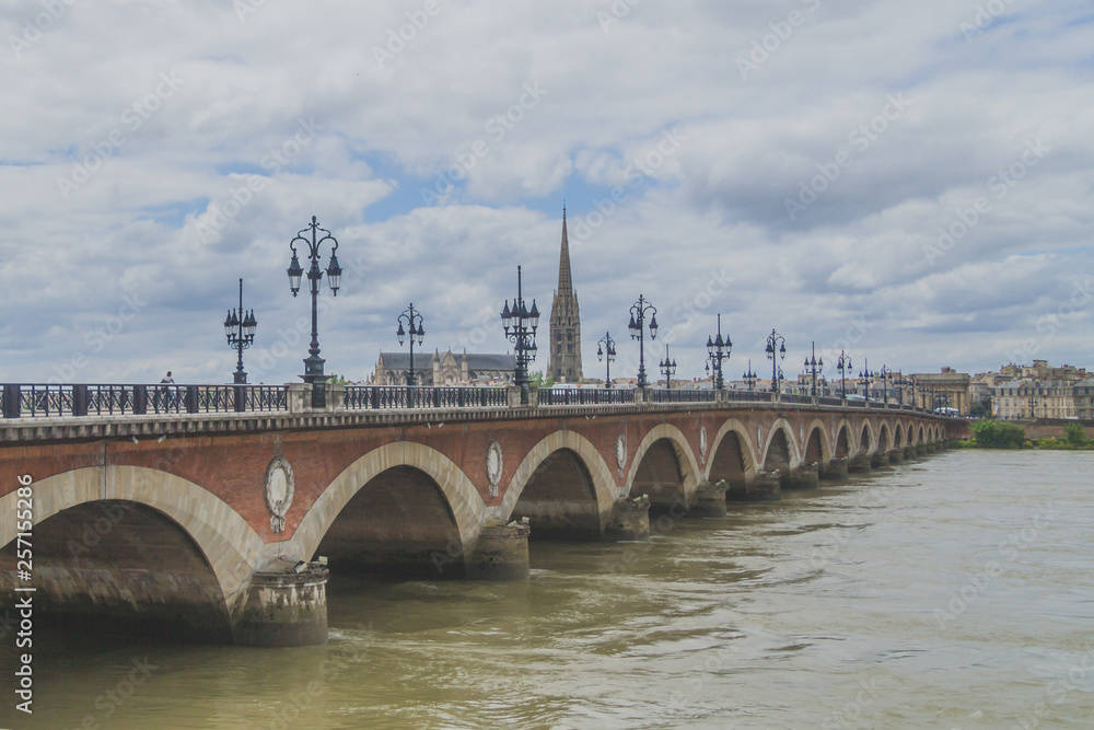 Pont de Pierre and Basilica of St. Michael with its tower under clouds ...