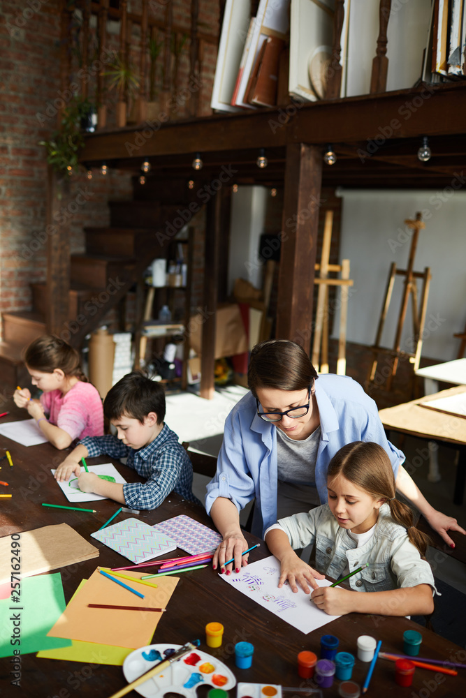 High angle portrait of modern young woman working with kids drawing ...