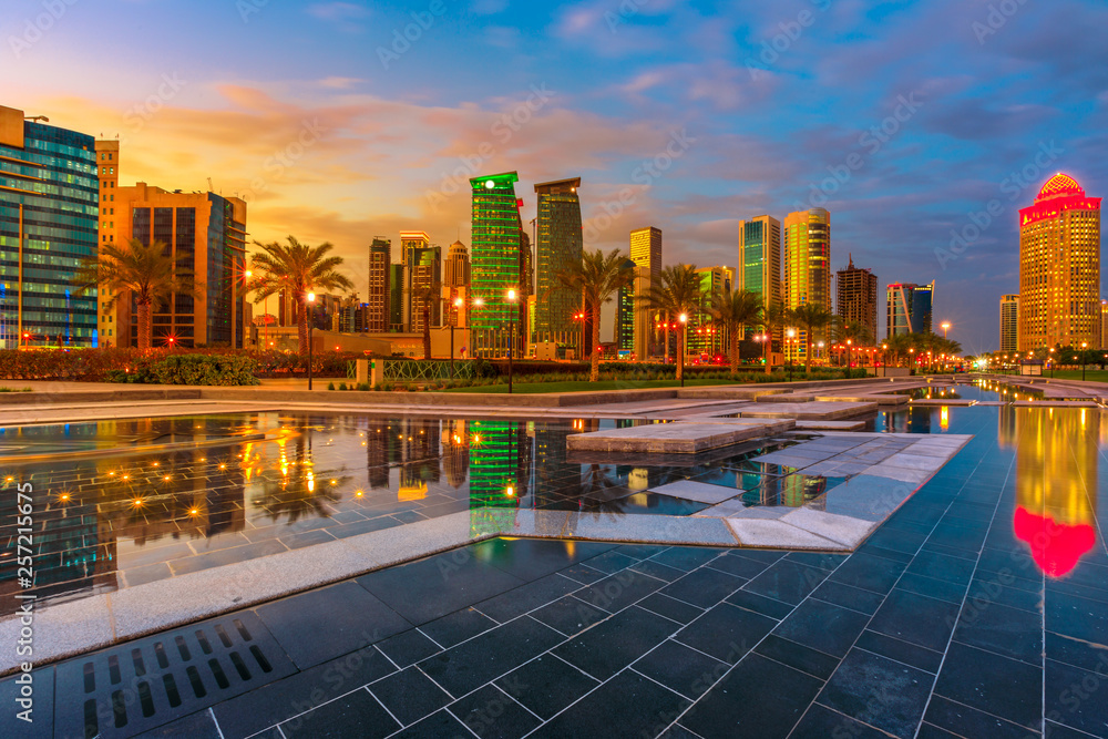 Doha West Bay skyscrapers at twilight reflecting in the water of park ...