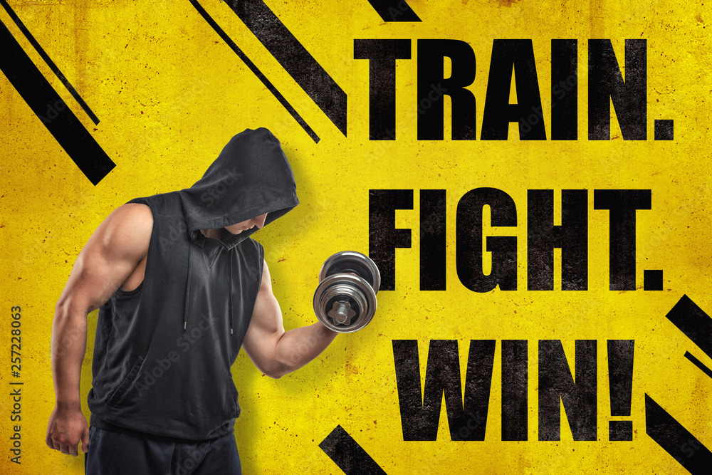 Strong muscular young man in black sportswear with a dumbbell and ...