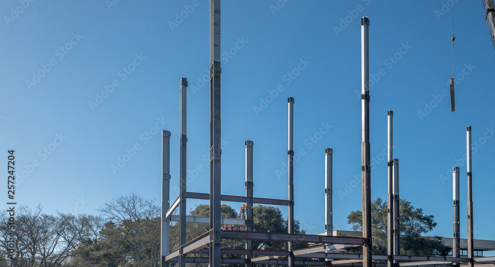 An ironworker is standing a horizontal steel I-beam and holding onto ...