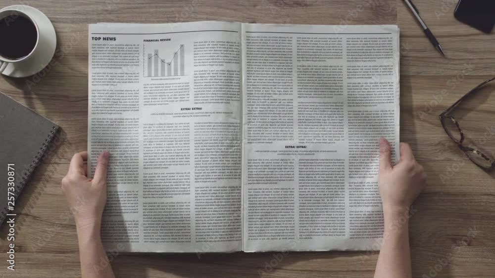 Hands open the the business Newspaper on wooden table in the office ...
