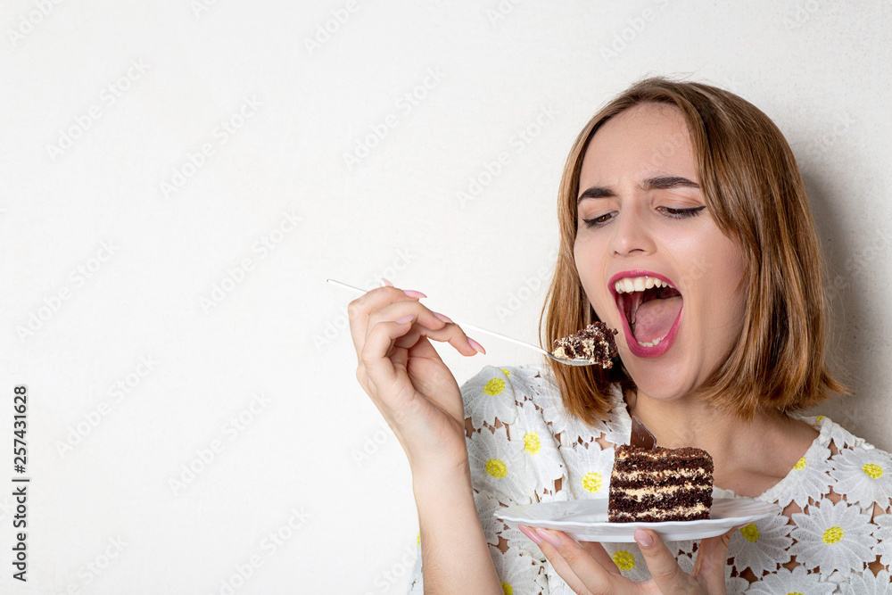 Pretty young girl eating tasty chocolate cake over white background ...