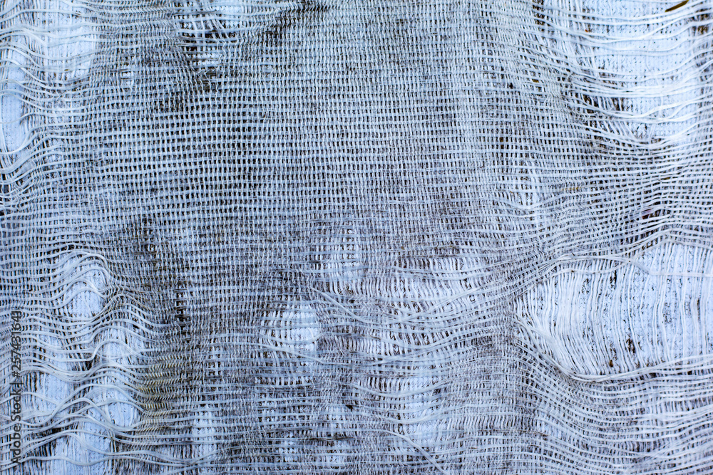 The texture of torn white fabric with a large cage or burlap, curtain ...