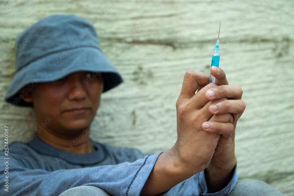 close up of Syringe and Needle in hand of drug addict man. homeless ...