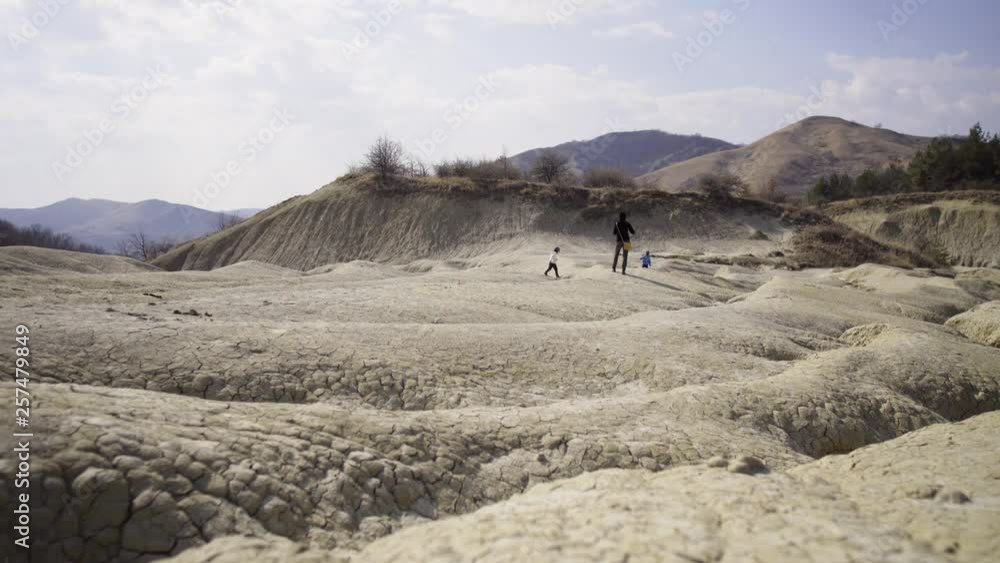 Mud volcanoes landscape with dried cracked soil. Two children walking ...