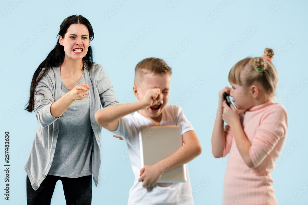 Angry mother scolding her son and daughter at home. Studio shot of ...