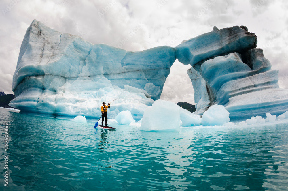 Man on stand up paddle board against iceberg Stock Photo | Adobe Stock