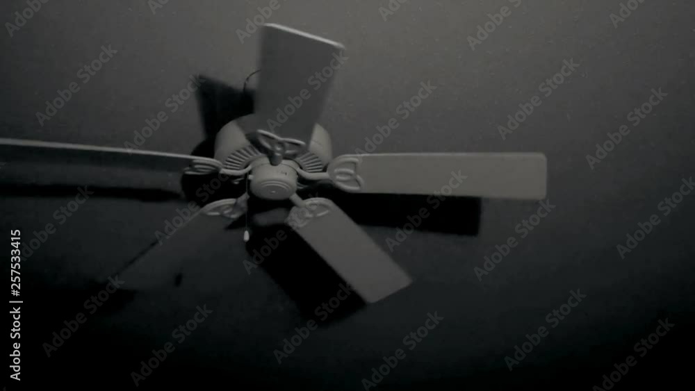 Rotating ceiling fan gradually slows down in dark room at night with ...