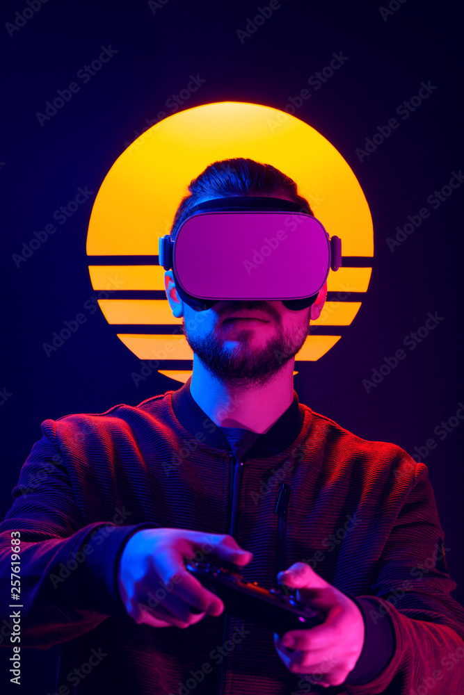 Man wearing virtual reality goggles playing video game with gamepad ...