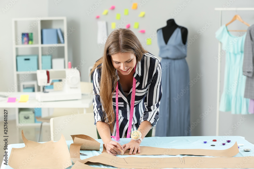 Beautiful female business owner working with sewing patterns in atelier ...