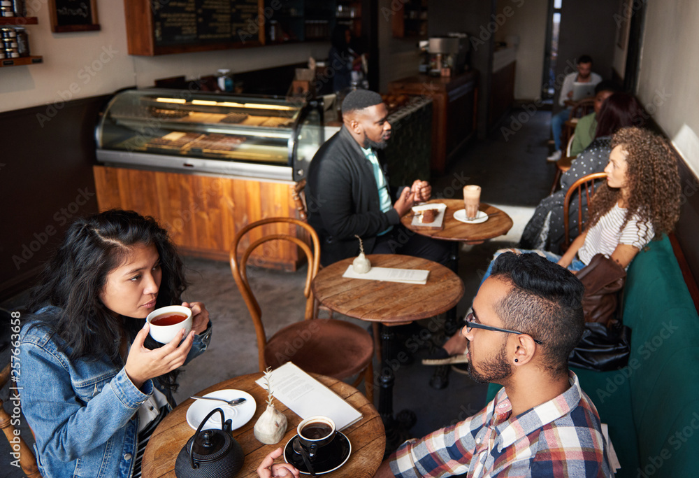 Multiethnic crowd sitting at tables in a trendy cafe Stock Photo ...