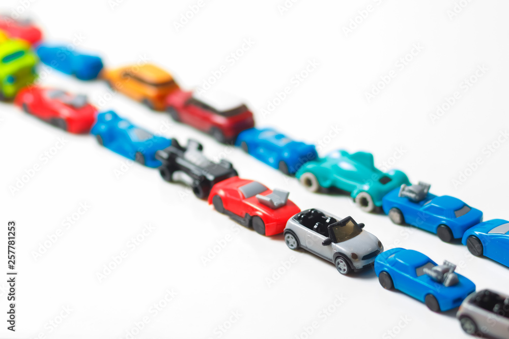 Plastic multi-colored toy cars are lined up on a white background ...