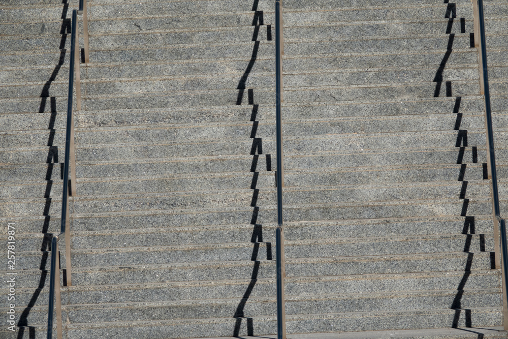 Broad concrete staircase with three banisters. It is outside and you ...