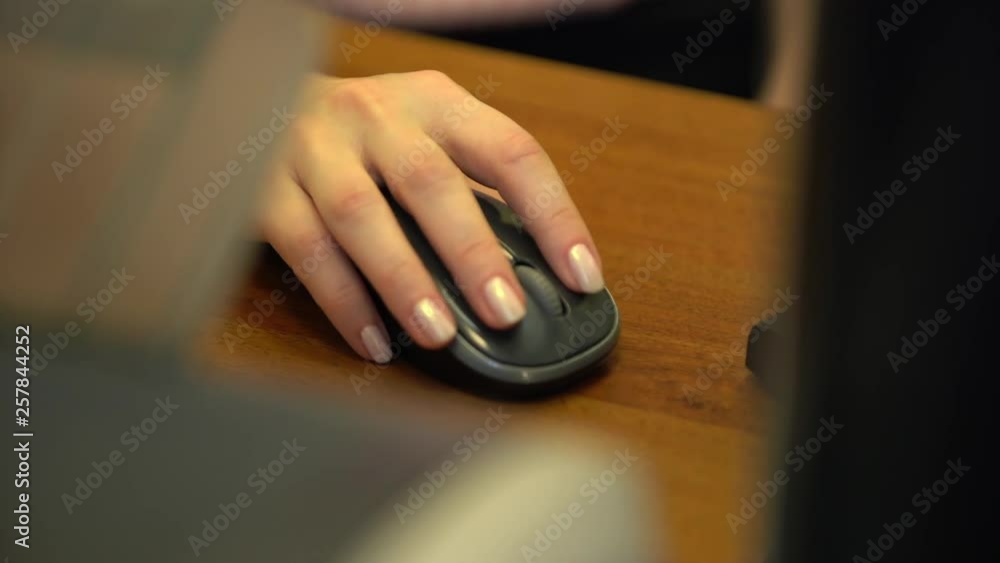 A woman's hand with a classic manicure lies on a computer mouse ...