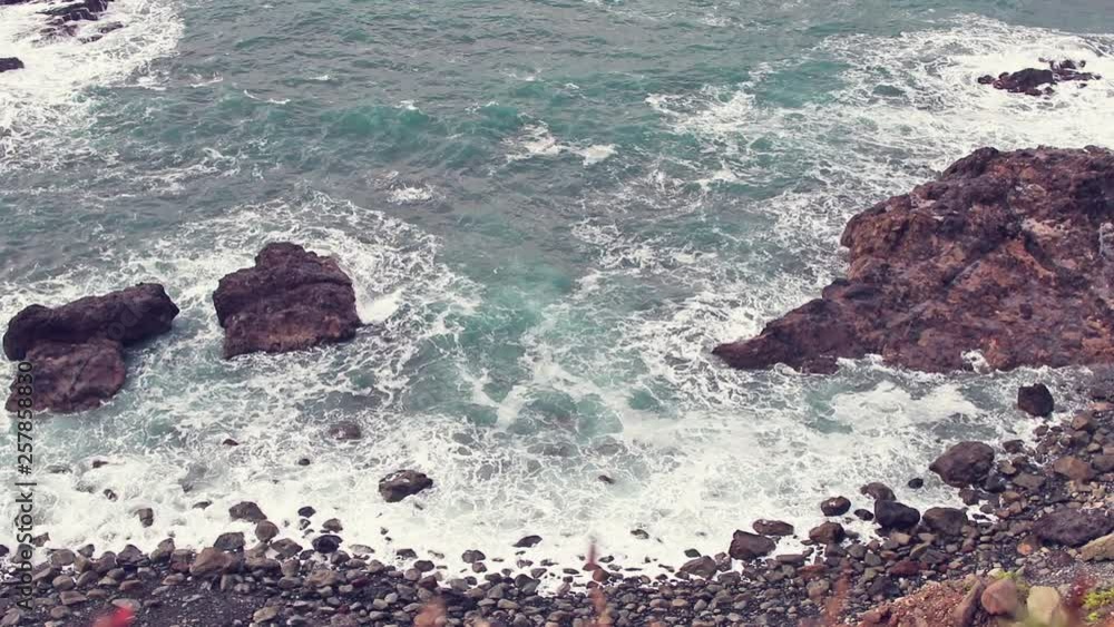 ocean waves crashing on volcanic rocks. sea with waves that create foam ...