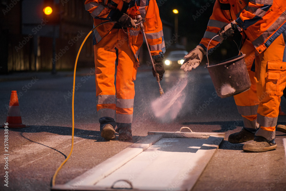 Traffic line painting. Workers are painting white street lines on ...