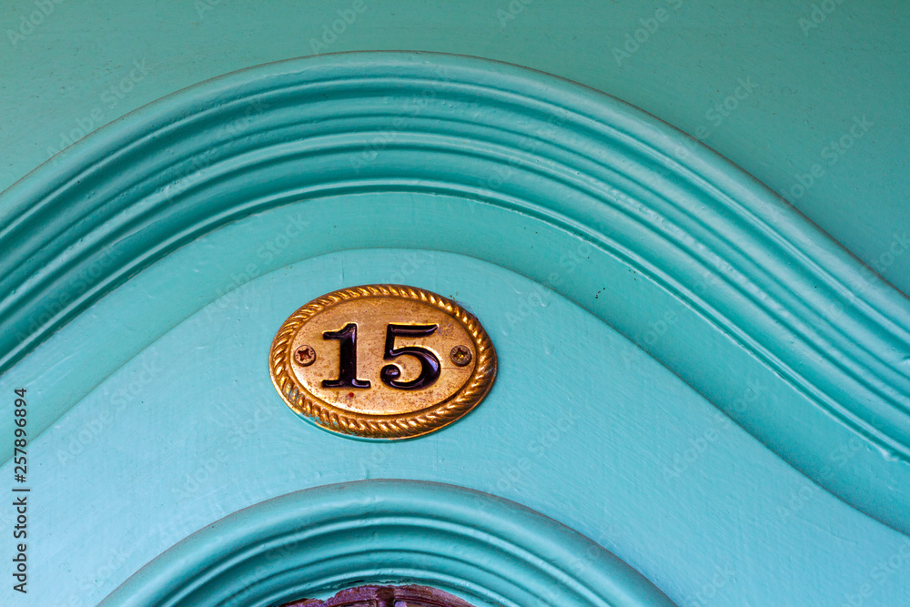 House number 15 with the fifteen in black on a bronze plaque screwed to ...