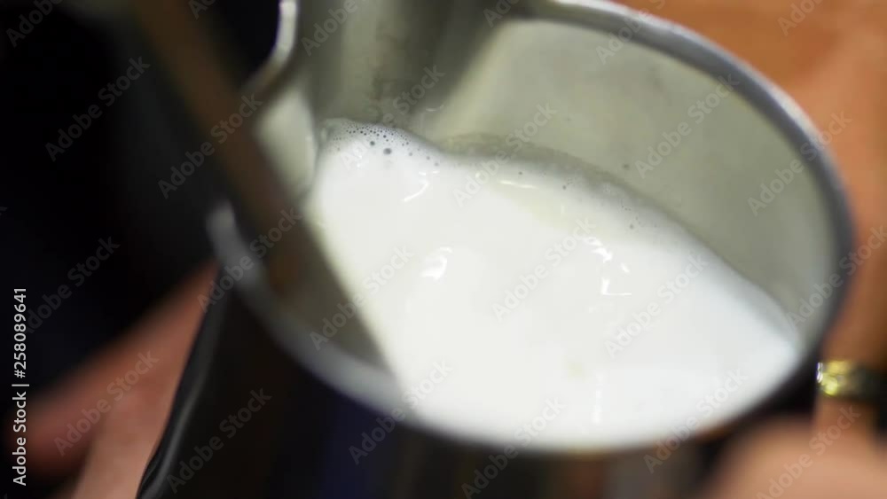 Whipping white milk in an iron coffee pot using a special tube of the ...