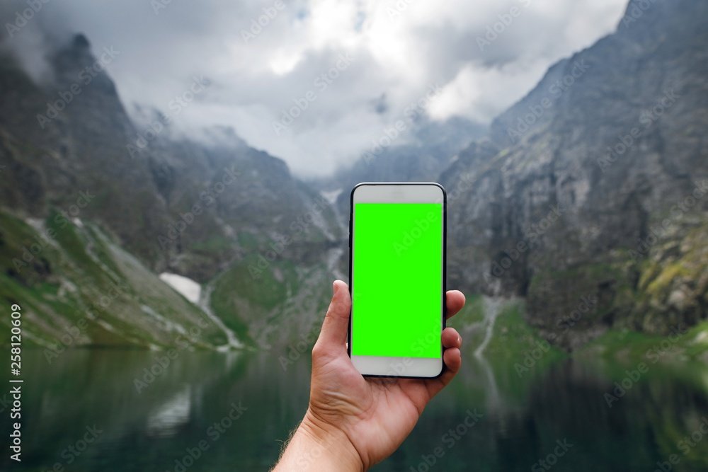 Man hand holding white smartphone with green screen on background with ...