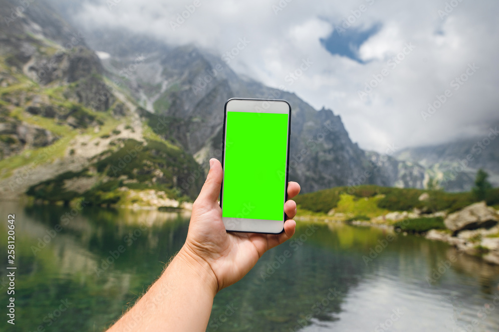 Man hand holding white smartphone with green screen on background with ...