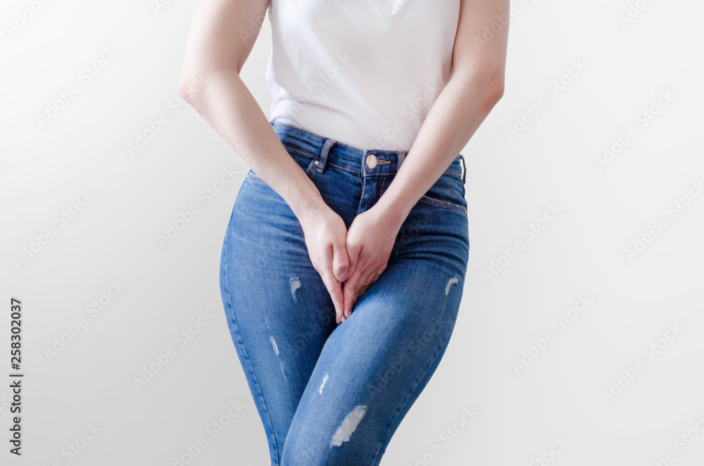 Young woman in jeans standing with her hands between legs Stock Photo ...