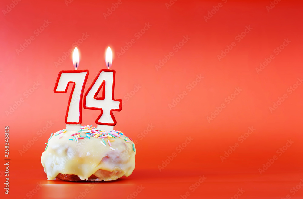 Seventy four years birthday. Cupcake with white burning candle in the ...