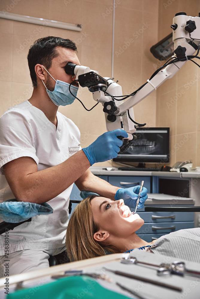 Your health is our priority. Male dentist look at the patient using ...