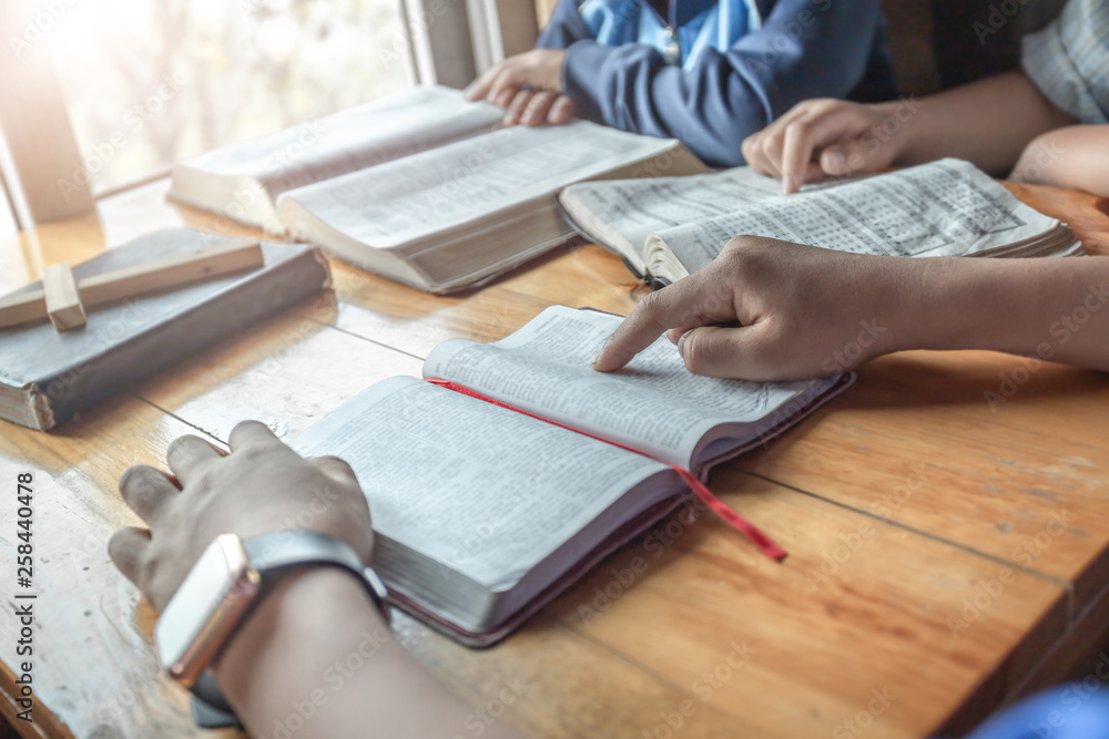 Children group reading holy bible together around wooden table with ...