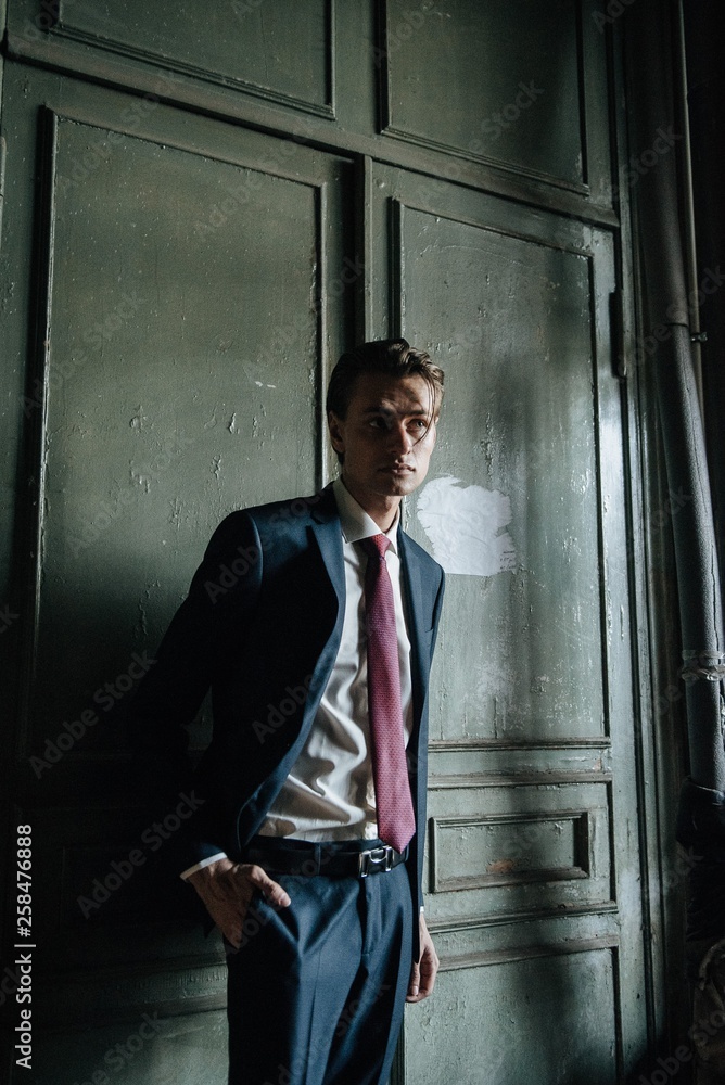 Male model in black suit and red tie poses for men's clothing ...