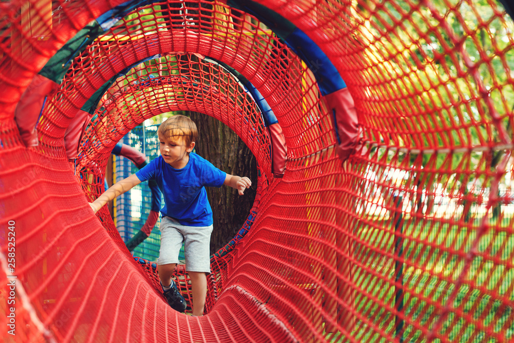 Happy kid overcomes obstacles in rope adventure park. Summer holidays ...