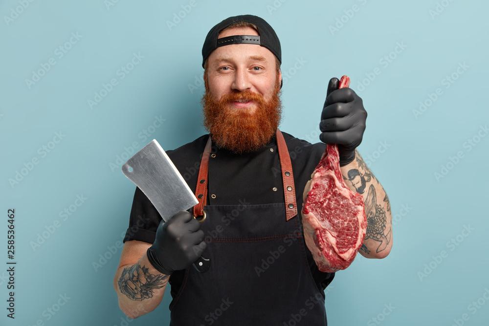 Positive ginger butcher work on manufacturing factory, holds cleaver ...