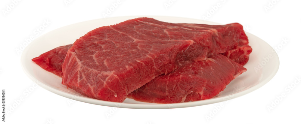 Slices of beef chuck boneless short rib steak on a plate atop white ...