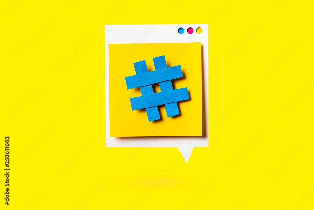 Paper cutout of hashtag symbol on a yellow speech bubble on yellow ...