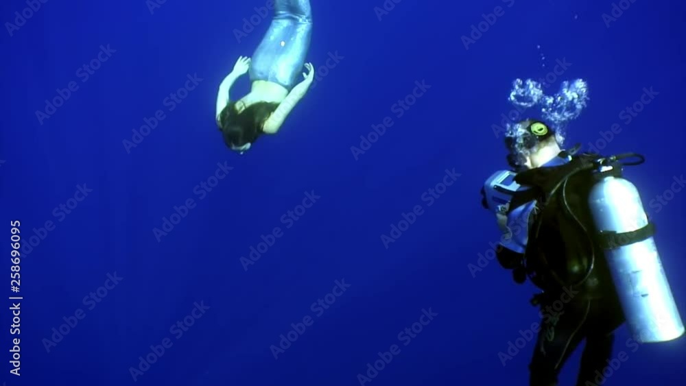 Young woman mermaid poses for camera of cameraman underwater in sea ...