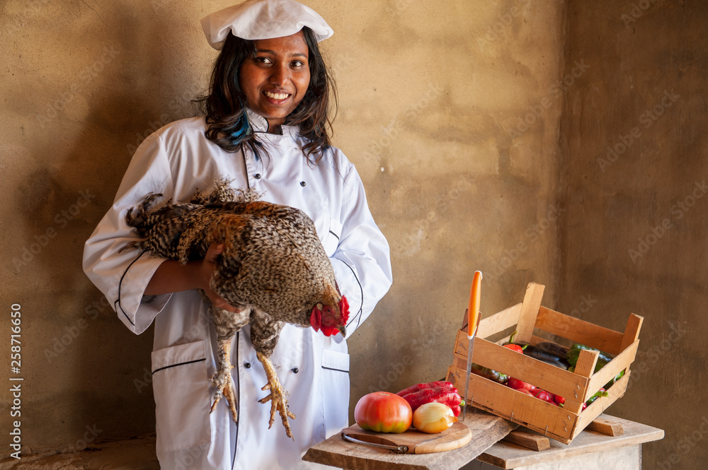 Attractive Indian woman cook posing in kitchen with chicken in her ...