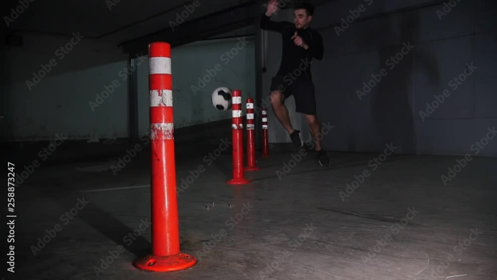 Underground parking lot. Athletic soccer man training his football ...