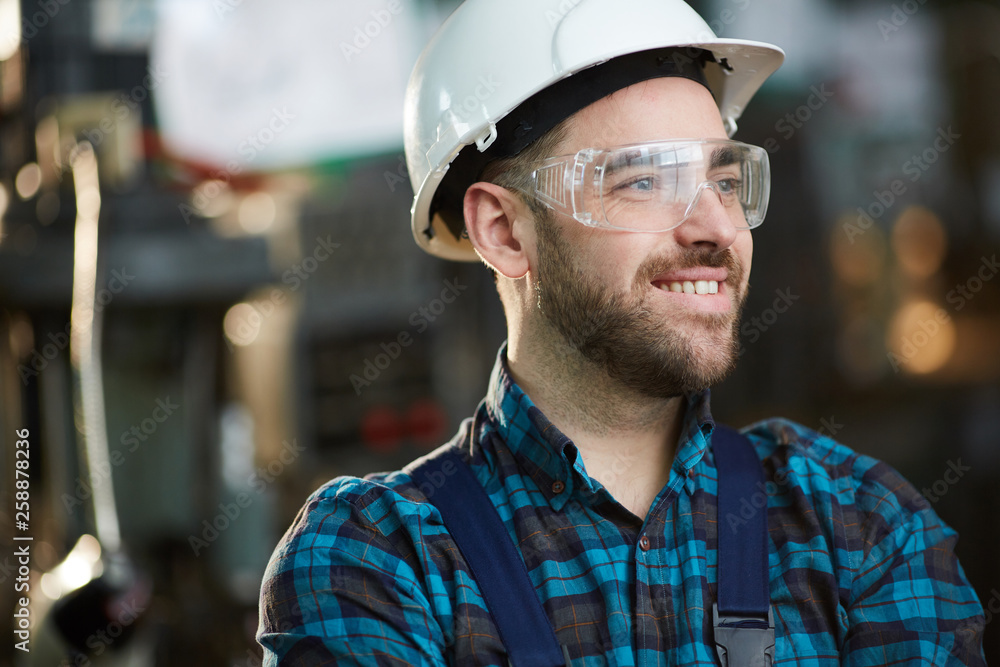 Head and shoulders portrit of bearded factory worker wearing hardhat ...